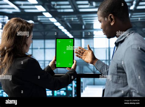 team of engineers working in server farm using chroma key tablet to
