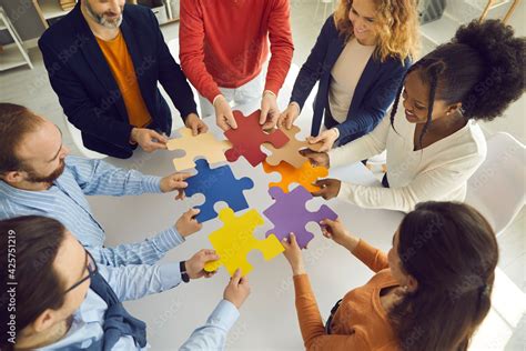 Diverse Team Connecting Puzzle Pieces As Metaphor For Finding Solution To Problem High Angle