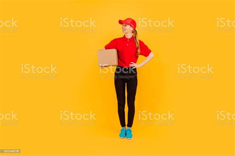 고립 된 노란색 배경에 골판지 상자를 들고 빨간 유니폼에 미소 택배 빠르고 무료 배달 가방에 대한 스톡 사진 및 기타 이미지