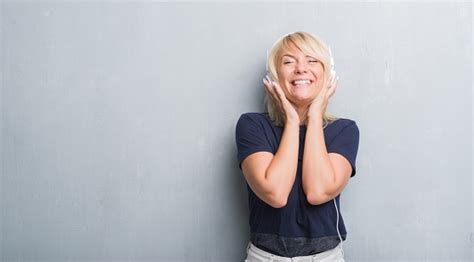 서 치아를 보여주는 자신감 미소로 웃 고 행복 한 얼굴로 헤드폰을 착용 하는 그런 지 회색 벽에 성인 백인 여자 건강한 생활방식에 대한 스톡 사진 및 기타 이미지 Istock