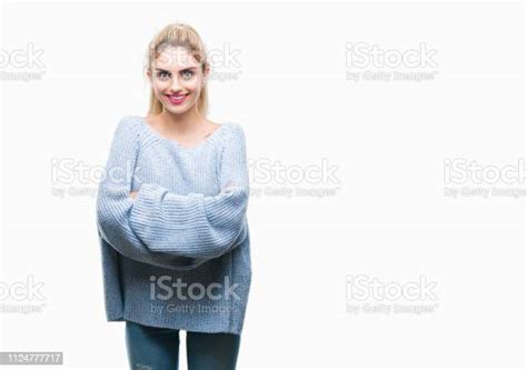 고립 된 배경 위에 겨울 스웨터를 입고 젊은 아름 다운 금발 파란 눈 여자는 카메라를 보고 교차 팔 웃는 얼굴 긍정적 인 사람