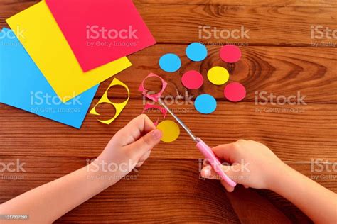 한 어린이가 가위와 종이를 들고 원을 자르고 있다 다채로운 종이 시트입니다 아이들을위한 기술을 절단 아이들을위한 가위 연습 갈색 나무 배경 가위에 대한 스톡 사진 및 기타
