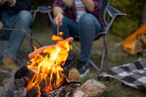 아름 다운 커플 앉아 캠프 파이어 주위에 캠핑 텐트와 배경에 남자 막대기로 화재 제스처 건강한 생활방식에 대한 스톡 사진 및 기타 이미지 Istock
