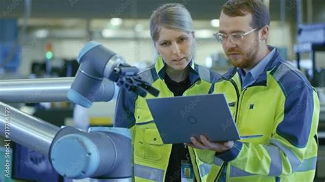 At The Factory Female Chief Production Engineer And Male Automation Engineer Use Laptop For