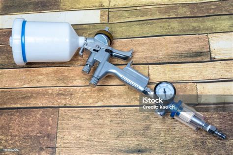나무 바닥에 페인트 스프레이 산업 회화 및 코팅에 사용되는 산업 크기 스프레이 건을 들고 화가의 팔 손의 이미지 배경 클리핑