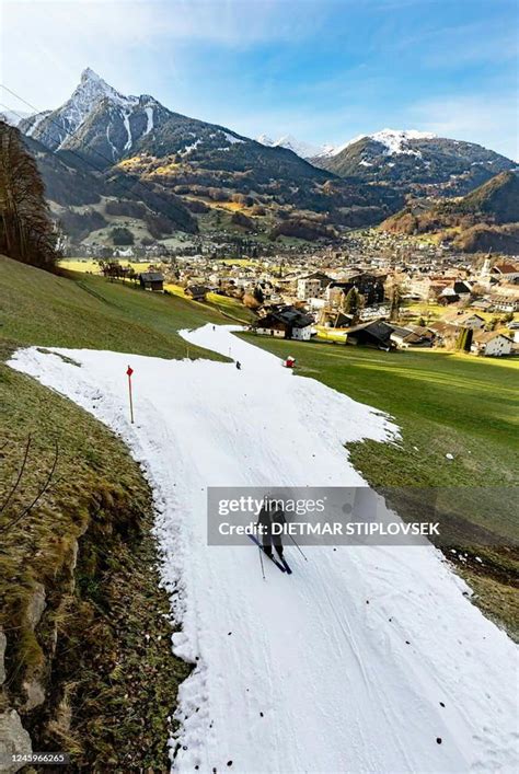 A Ski Tourist Slides Down A Ski Slope Amidst Green Areas In Schruns