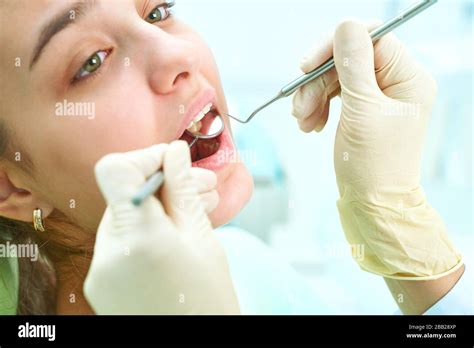 Girl Sitting At Dental Chair With Open Mouth During Oral Check Up While