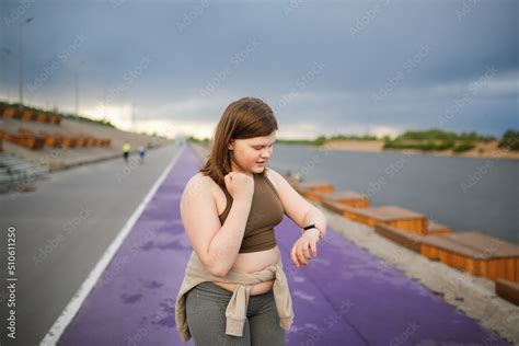 European Teenage Girl Overweight On Jog On Treadmill Along Embankment
