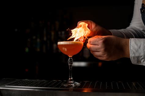 스틸 바 카운터에서 칵테일 한 잔을 클로즈업하고 바텐더의 손이 그 위에 불을 붙입니다 결정체에 대한 스톡 사진 및 기타 이미지