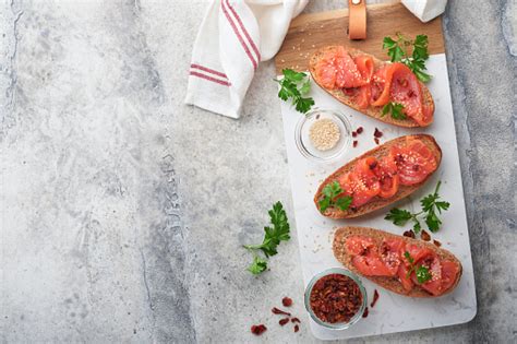 소금에 절인 연어 샌드위치 흰색 대리석 스탠드에 소금에 절인 연어 참깨 및 말린 토마토를 곁들인 시리얼 또는 곡물 호밀 빵에서 샌드위치를 엽니 다 해산물 건강에 좋은 음식