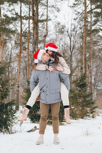 산타 모자를 쓰고 겨울 철엽 숲에서 포옹하고 장난을 치며 커플 커플에 대한 스톡 사진 및 기타 이미지 커플 크리스마스