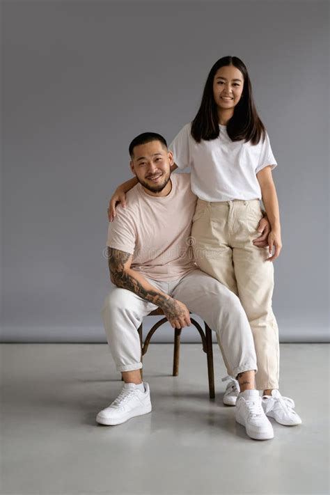 Stylish Asian Couple Hugging And Looking At Camera On Grey Background