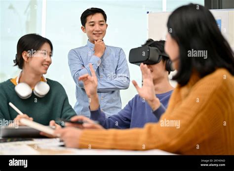 A Cheerful Asian Male Developer Sitting At The Table Tested A New Vr Game With Virtual Reality
