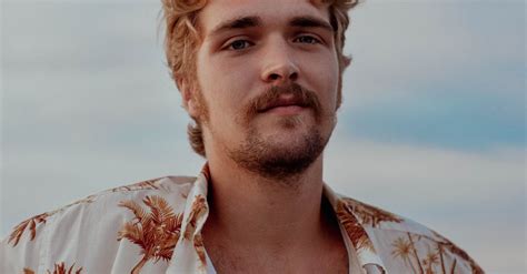 가벼운 감각 개인 걱정 없는 고요한 금발 꽃 무늬 셔츠 나타내는 남성 의류 눈맞춤 따뜻한 레저 맑은 날 맑은 하늘 미니멀리스트 미소 부드러운