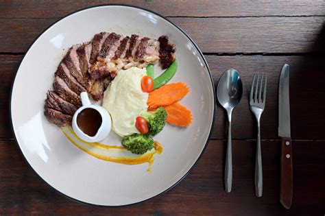 최고보기 프리미엄 품질 호주 쇠고기 스테이크 검은 후추 소스와 흰색 접시와 나무 테이블 배경에 칼 숟가락 포크에 야채 식품 개념입니다 0명에 대한 스톡 사진 및 기타 이미지