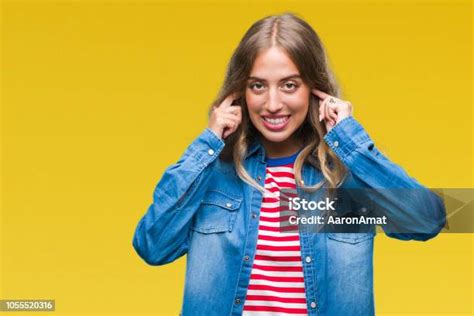 시끄러운 음악의 소음에 대 한 짜증이 식이 손가락으로 귀를 덮고 격리 된 배경 위에 아름 다운 젊은 금발 여자 청각 장애인