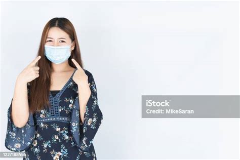 코로나바이러스를 보호하기 위해 의료 보호 페이스 마스크를 착용한 아시아의 아름다운 행복한 힙스터 여성 필터 먼지 Pm 25 및 추위와 흰색 배경에 그녀의 손가락 포인트