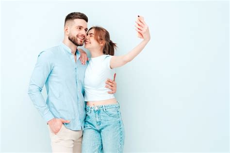 웃는 아름다운 여자와 그녀의 잘생긴 남자친구 스튜디오의 밝은 파란색 벽 근처에서 부드러운 순간을 보내는 행복한 쾌활한 가족 무료 사진