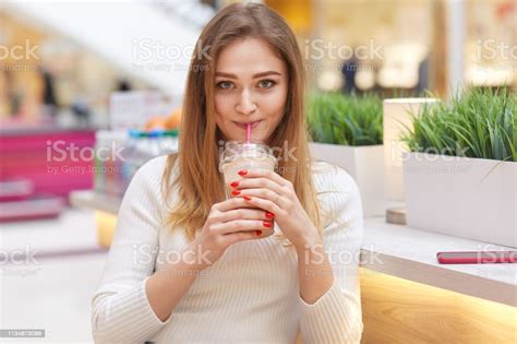 흰색 점퍼를 입고 매력적인 사랑 스러운 여자의 이미지는 우유 칵테일을 보유 카메라에 보인다 친구 들과 여가 시간을 보낸다 다른