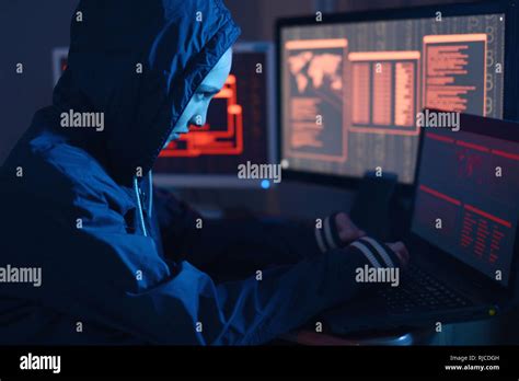 Girl Hacker In A Hood Typing Program Code While Committing A Cybercrime