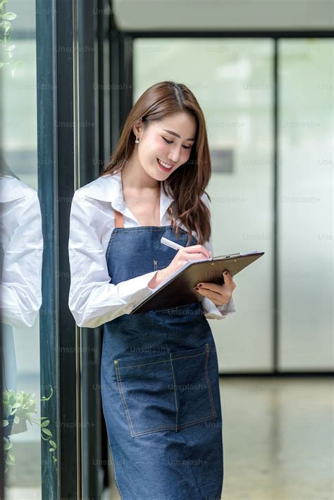 아름 다운 젊은 아시아 여성 기업가가 큰 거울 옆에 서서 메모하고 있습니다 사진 Unsplash의 사람 이미지