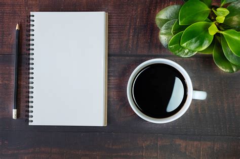나무 테이블 배경에 빈 페이지 연필 식물과 커피 컵 오픈 학교 노트북의 상단보기 복사 공간이 있는 비즈니스 사무실 또는 교육