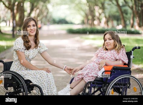 Pretty Caucasian Women In Wheelchairs Holding Hands And Smiling On