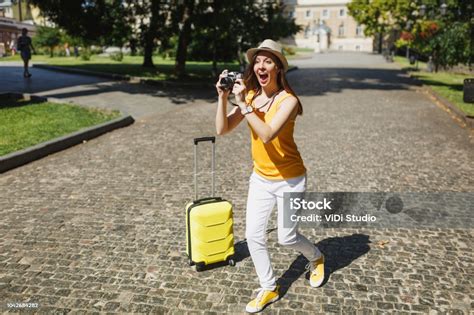 충격된 여행자 관광 여자 가방와 노란색 캐주얼 옷에서 복고 빈티지 사진 카메라 야외 실행에 사진을 찍을 주말도 주에 해외 여행을 하는 소녀 관광 여행 생활양식입니다