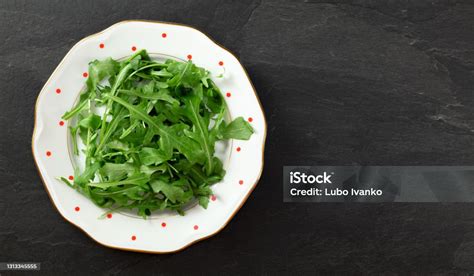 신선한 녹색 아루굴라 또는 정원 로켓은 빨간색 점 검은 색 테이블 이있는 흰색 접시에 남깁니다 건강한 채소와 샐러드 컨셉 건강한 식생활에 대한 스톡 사진 및 기타 이미지