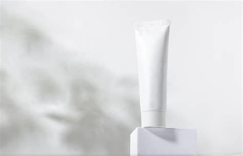 나뭇잎과 그림자가 있는 스탠드에 흰색 화장품 튜브 치약 얼굴 바디 크림 스킨 케어 제품이 있는 여성 화장품 튜브 유기농 화장품