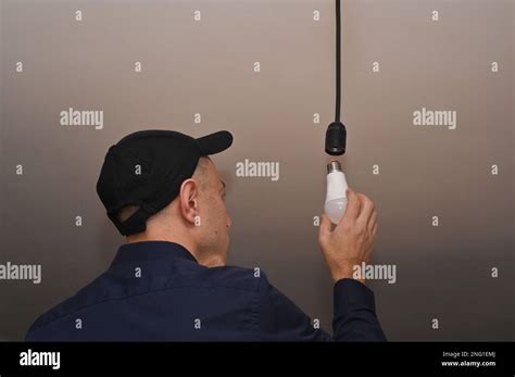 A Man Screws In A Light Bulb Installation Of The Led Lamp Stock Photo Alamy