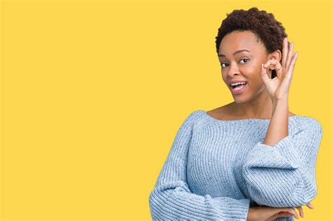 젊은 아름 다운 아프리카계 미국인 여자 손과 손가락으로 Ok 사인을 하 고 긍정적인 미소 격리 된 배경 위에 스웨터를 입고