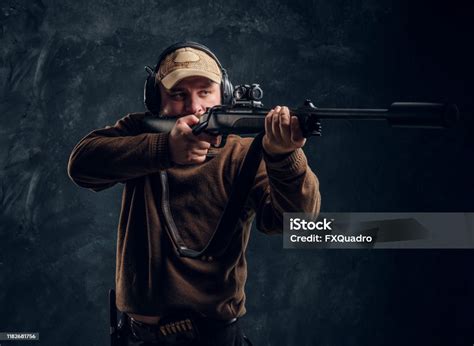 Pemburu Pria Bertiat Dan Headphone Memegang Senapan Dan Membidik Target
