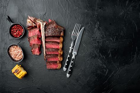 신선한 육즙 매체 희귀 슬라이스 와 구운 T 뼈 또는 포터 하우스 쇠고기 고기 스테이크 검은 돌 배경에 상단 보기 플랫 레이