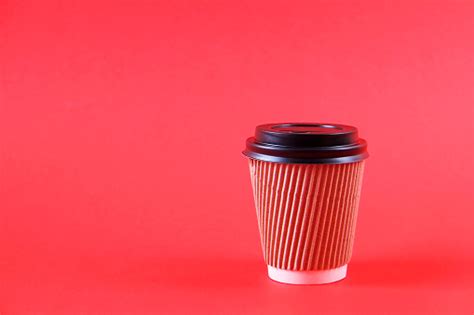 갈색 일회용 안전 내 열 두 배 벽된 종이가 커피의 컵을 꺼내 뜨거운 음료 밝은 빨간 배경에 백색 모자에 대 한 다채로운 에코친화적인 종이 얼굴 복사 공간을 닫습니다 0명에