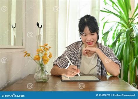 Young Asian Woman Using Stylus Pen Drawing On Digital Tablet Working On Design Project In