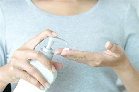 깨끗 한 노란 병 소프트 라이트 배경으로 얼굴의 세럼 콜라겐 보습제를 떨어 뜨 리고 아름 다운 여자의 손 프로텍터 스킨 트리트먼트 페이셜 에센스 오일 비타민 C 미용 및