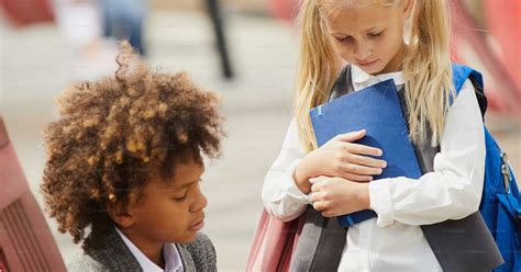 Two School Classmates Reading Book And Working Together In Team While Sitting Outdoors At
