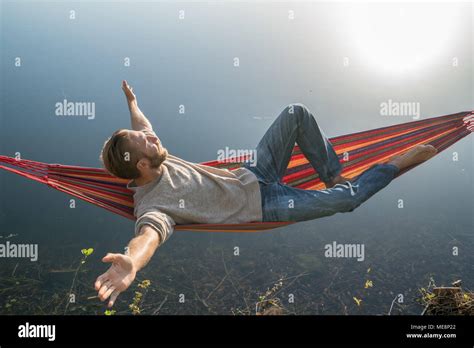 Young Man On Hammock By The Lake Embracing Nature With Arms Wide Open