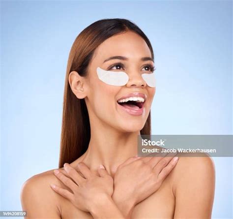 아름다움 콜라겐 그리고 파란색 배경 모형에 노화 방지 스킨케어를 위한 아이 마스크를 쓴 행복한 여자 화장품 얼굴 수리 및 히스패닉 모델의 얼굴과 디톡스 트리트먼트 제품이