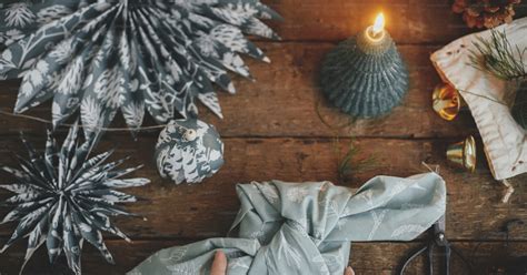 크리스마스 선물을 들고 있는 손은 촛불 장식품 파란색 종이 별이 있는 소박한 나무 테이블에 천으로 싸여 있습니다 분위기