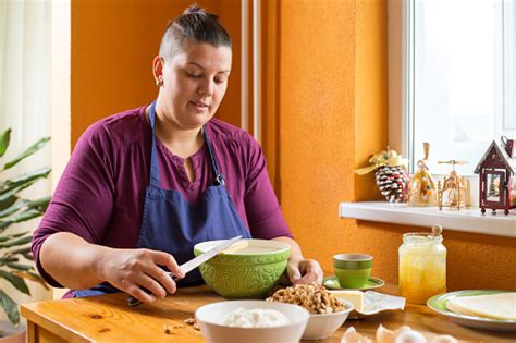 나무 식탁 그녀의 손에 칼을 들고와 그릇의 가장자리에 버터 한 조각을 닦아에 초점 뒤에 앉아 젊은 여자의 사진을 닫습니다 가정 생활에 대한 스톡 사진 및 기타 이미지