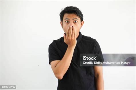 젊은 아시아 남성은 손으로 입을 다물고 흰색 바탕에 고립된 검은색 폴로 티셔츠를 입고 충격적인 표정을 짓고 있다 25 29세에 대한 스톡 사진 및 기타 이미지 Istock