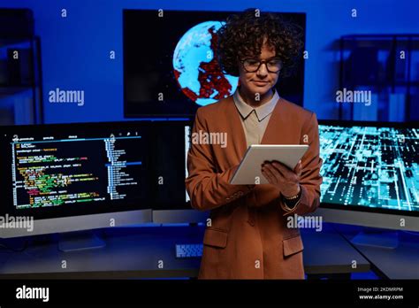 Young Serious Female Programmer Using Tablet While Standing Against