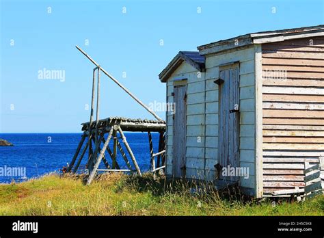 A Fishing Stage And Fishing Sheds On A Grassy Hill Next To The