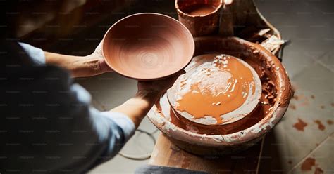 스튜디오에서 도자기 바퀴 옆에 서 있는 동안 토기 그릇을 들고 있는 여성 도예가의 클로즈업 사진 Unsplash의 도기 이미지