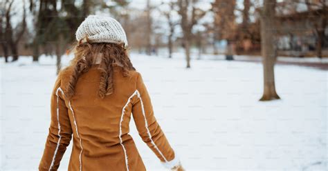 니트 모자와 양가죽 코트를 입은 중년 여성이 겨울에 도시 공원에서 바깥을 걷고 있는 모습 사진 Unsplash의 체코 이미지