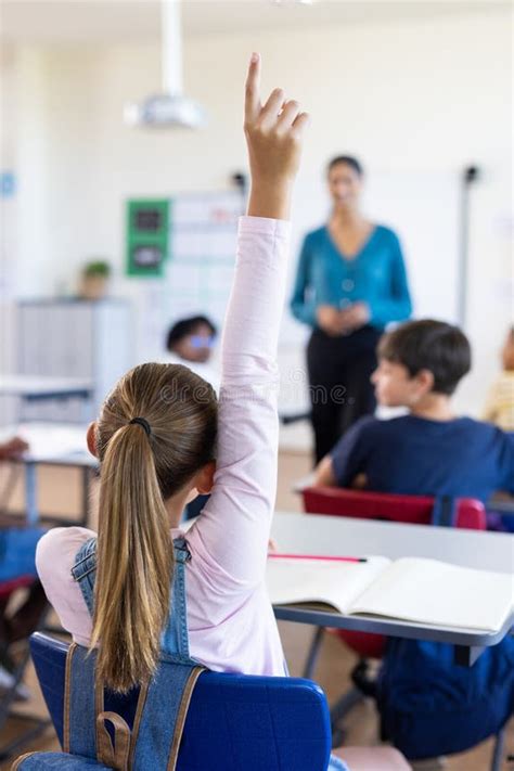 In School Girl Raising Hand To Ask Question In Classroom With Indian Female Teacher Stock Image