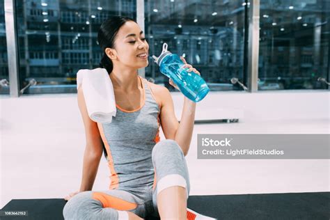 피트 니스 매트와 체육관 스포츠 병에서 식용 수에 앉아 어깨에 흰색 수건으로 슬림 아시아 소녀 건강한 생활방식에 대한 스톡 사진 및 기타 이미지 Istock