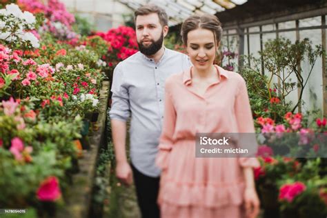 화려한 진달래 꽃 사이에 있는 유리 온실에서 젊은 사랑스럽고 쾌활한 백인 커플 행복한 발렌타인 데이 사랑 남자와 여자의 공생 개념 2명에 대한 스톡 사진 및 기타 이미지